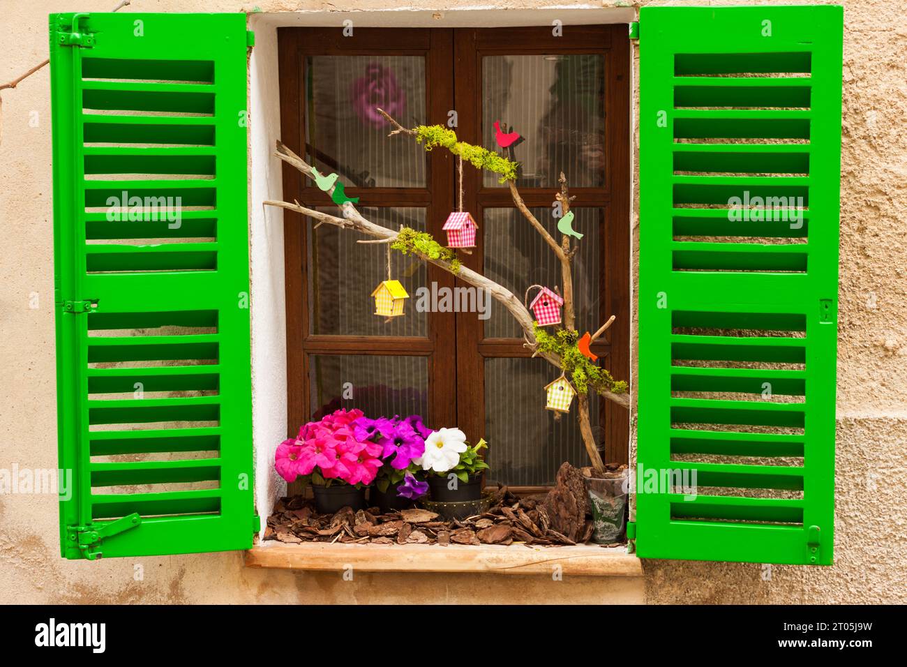 Window with green shutters, decorated with a branch with some hanging ...
