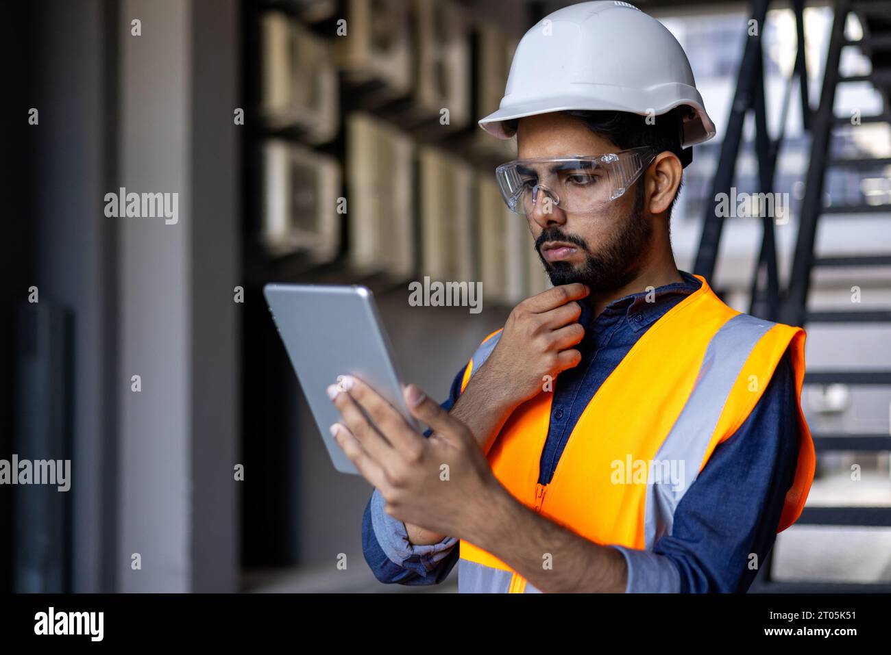Serious Thinking And Focused Engineer Working In Factory In Hard Hat