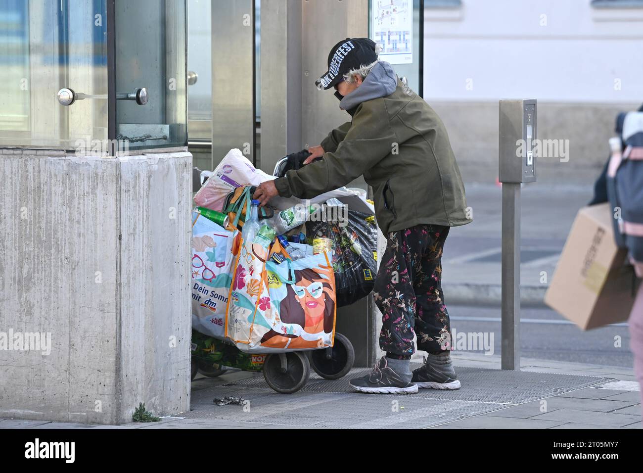 Frau, Bettlerin, Obdachlose schiebt einen Rollator, an dem volle ...