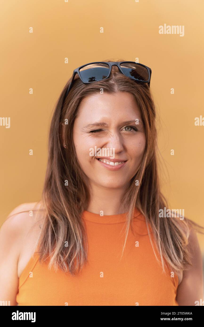 Portrait of a woman with sunglasses on her head winking an eye and ...