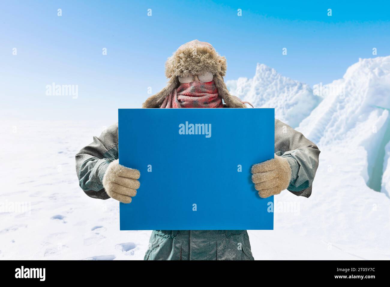 A Caucasian man holding a blank blue sign while bundled up in a fur ...