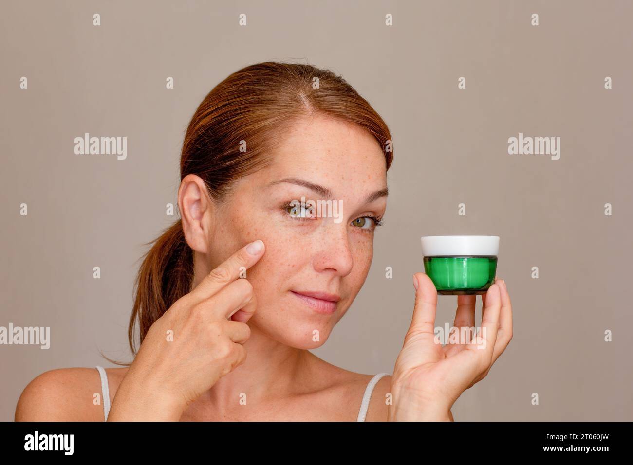 Portrait of middle aged woman with freckles showing on skin by index ...