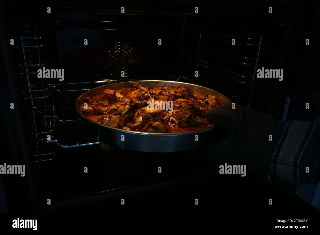 oven-baked chicken dish.taking food out of the oven Stock Photo - Alamy