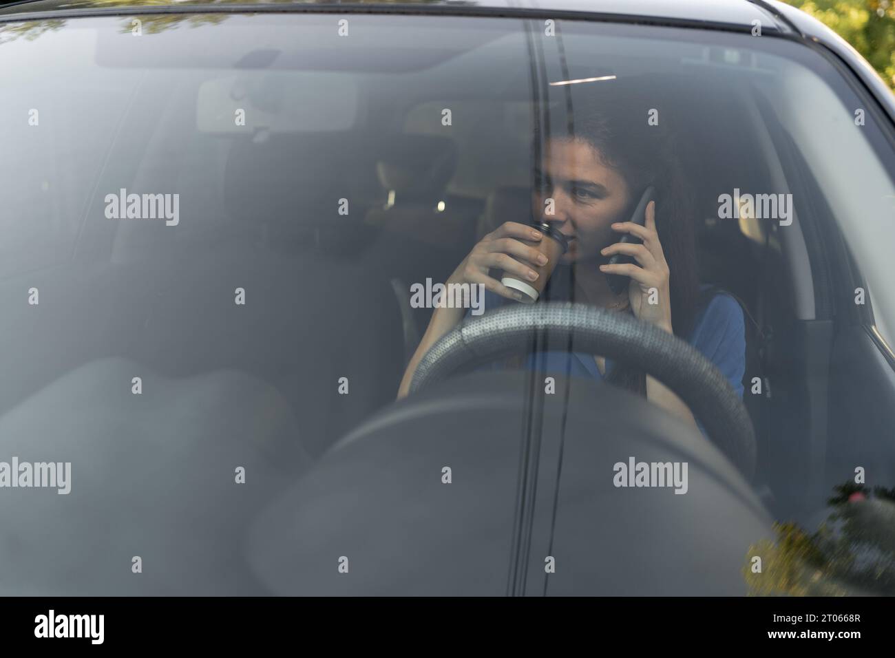 Multitasking driver business lady driving a car drinking coffee and ...