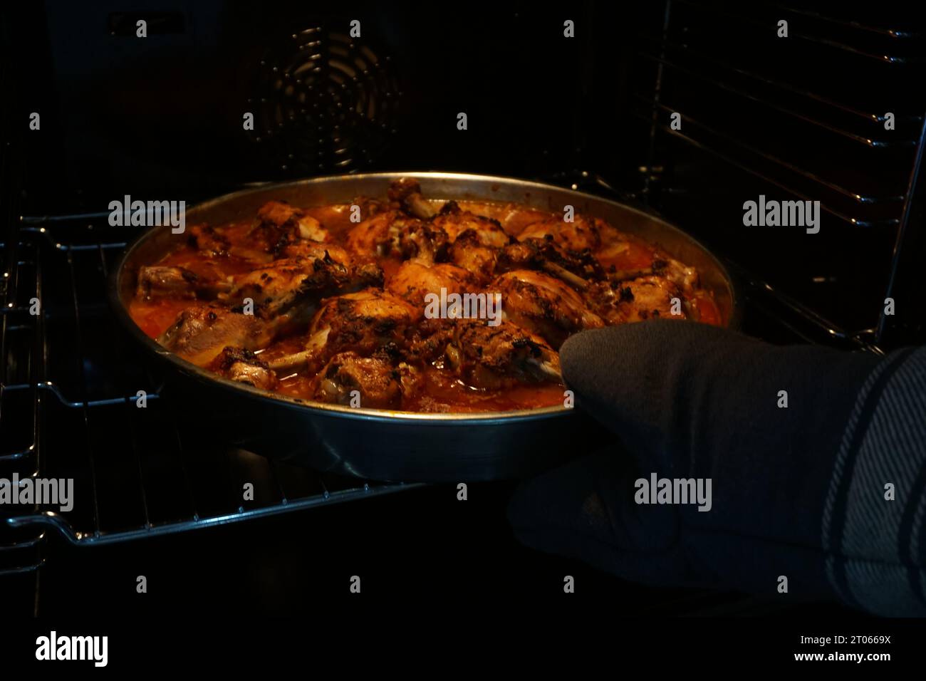 oven-baked chicken dish.taking food out of the oven Stock Photo - Alamy