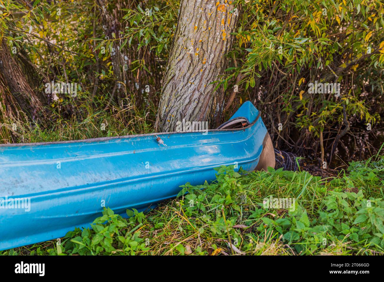 Close-up view of blue rowing metal boat parked on shore of river in ...