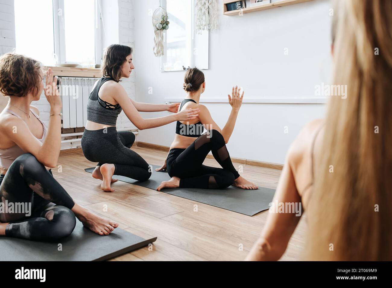 The teacher guides the student in yoga class, suggesting the correct ...