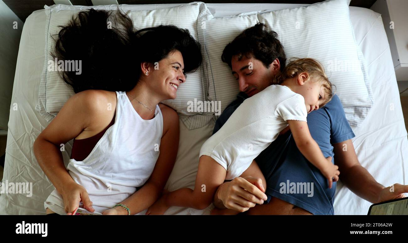 Millennial couple in bed with infant toddler boy wanting attention. Man ...