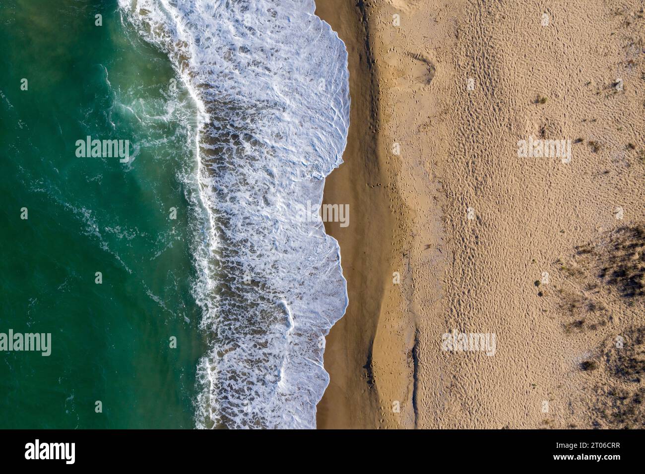 Aerial view of ocean waves washing a secluded sandy shoreline beach ...