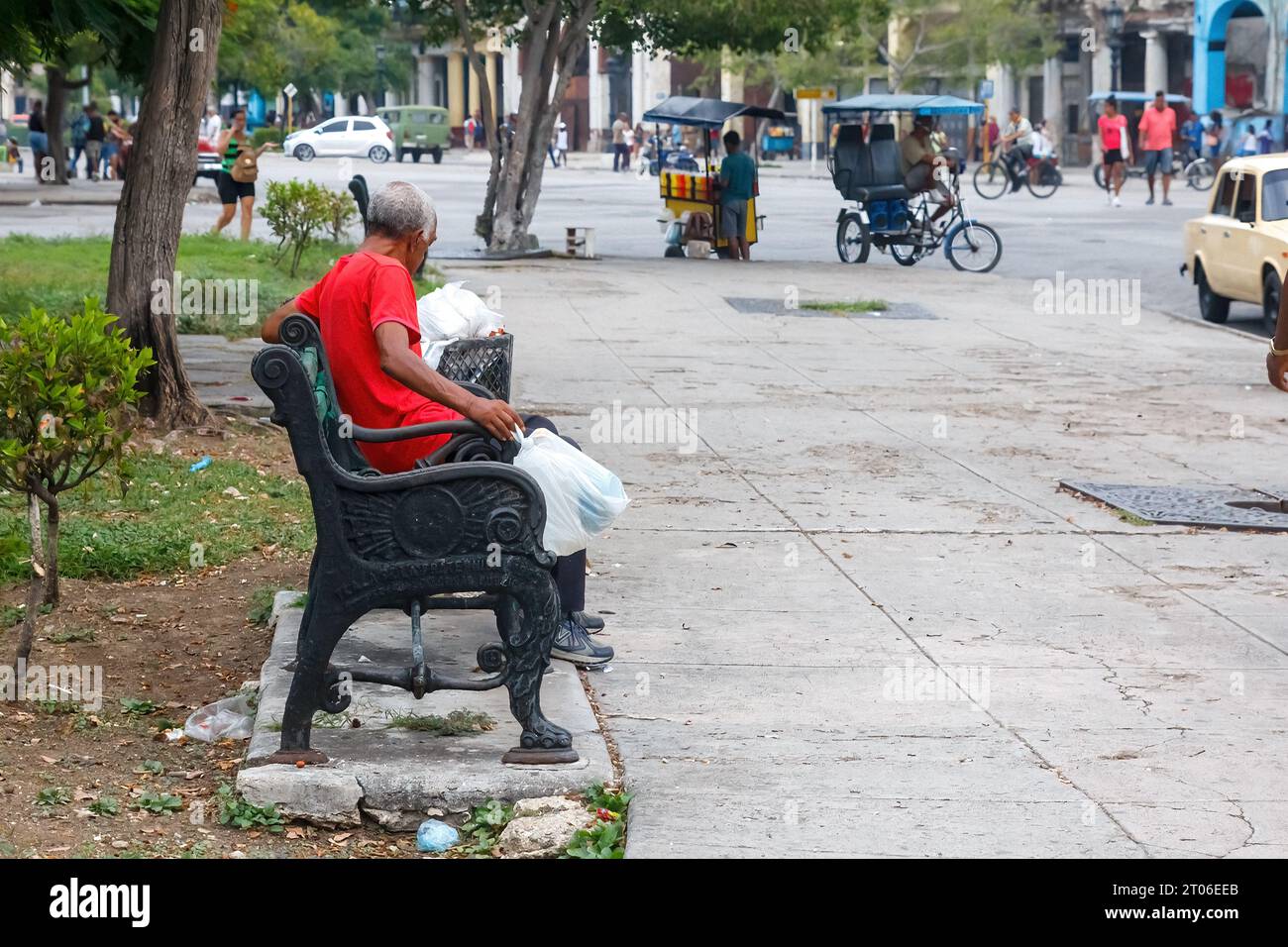 A Cuban person sits on a bench in a public park or square in the ...