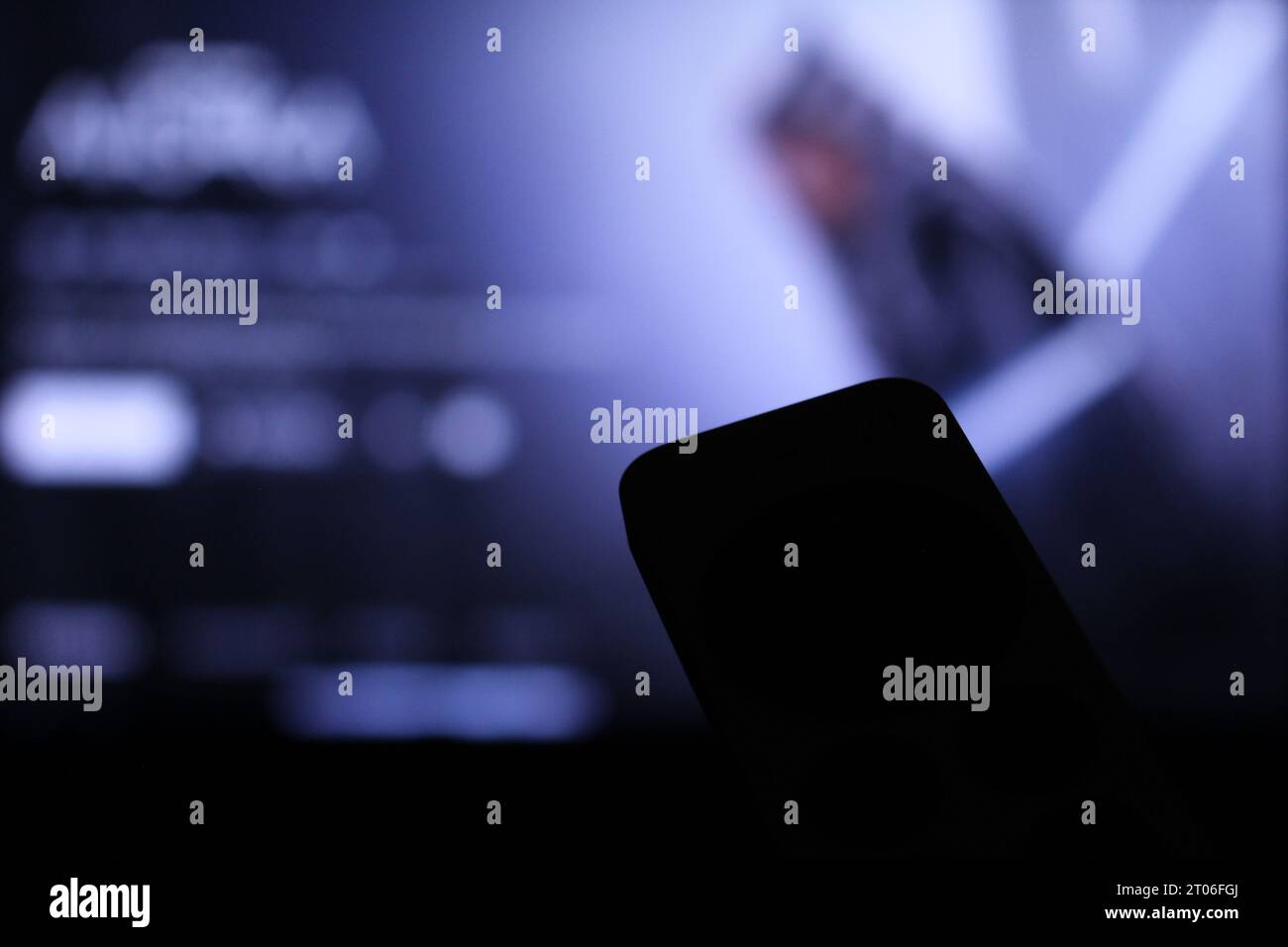 Shadow of a tv remote in front of a blurry tv screen playing a film ...