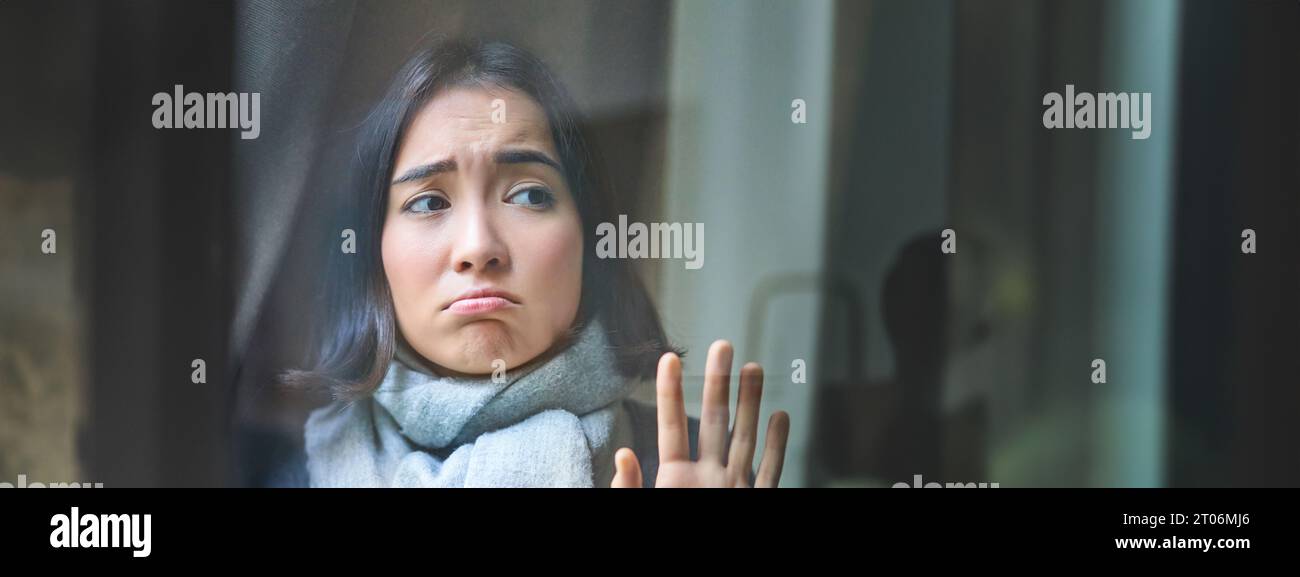 Vertical Shot Of Upset Asian Woman Looking Outside Touching Window
