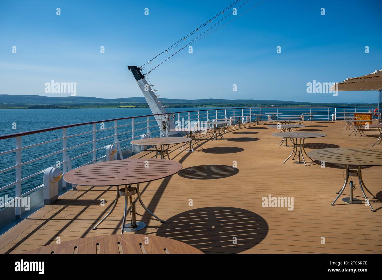 Empty backside boat deck with wooden tables of a cruise ship during ...