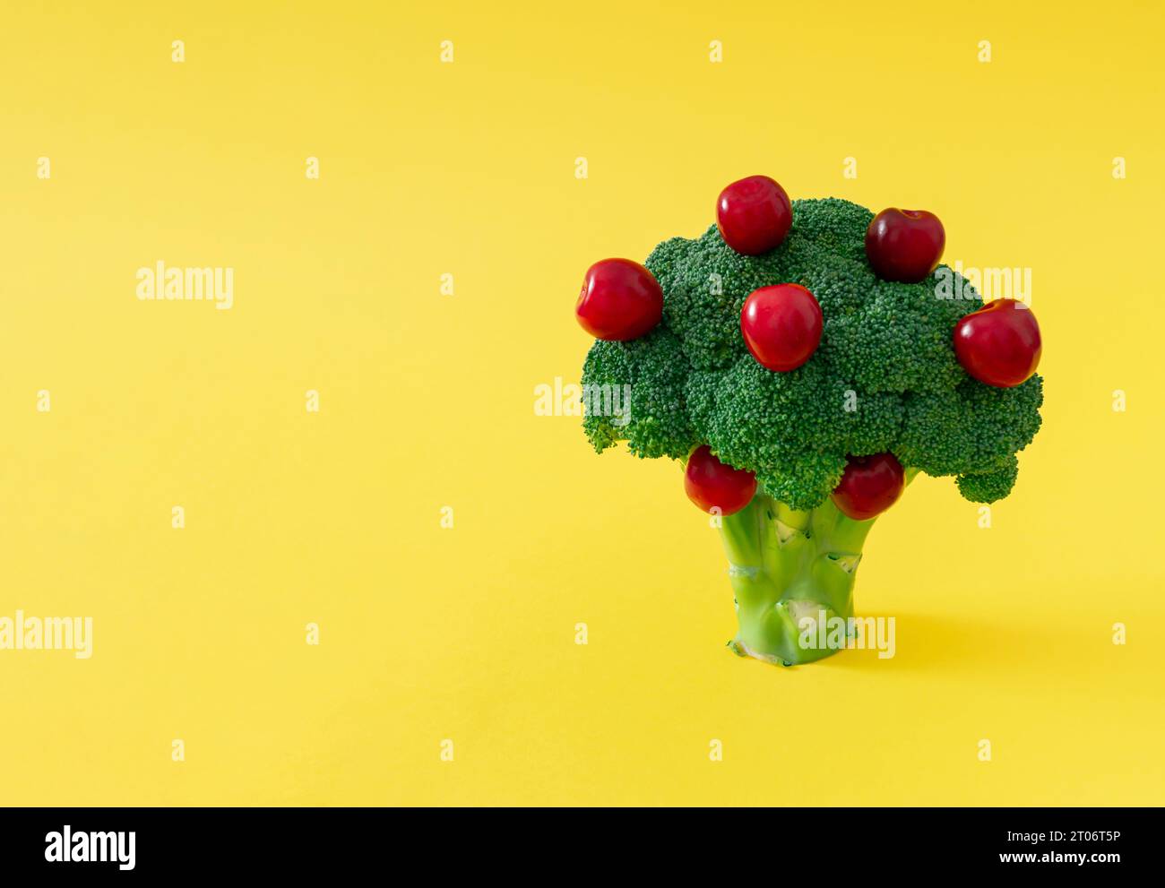 Fruit tree made of green broccoli and red cherries on pastel yellow ...