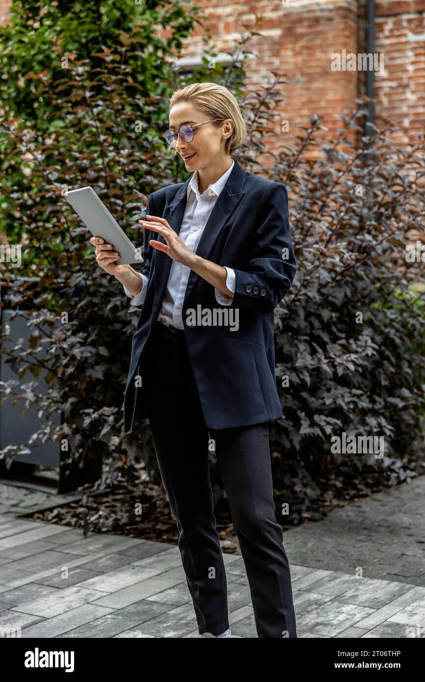 Cute young manager in jacket and pants with a tablet looking busy Stock ...