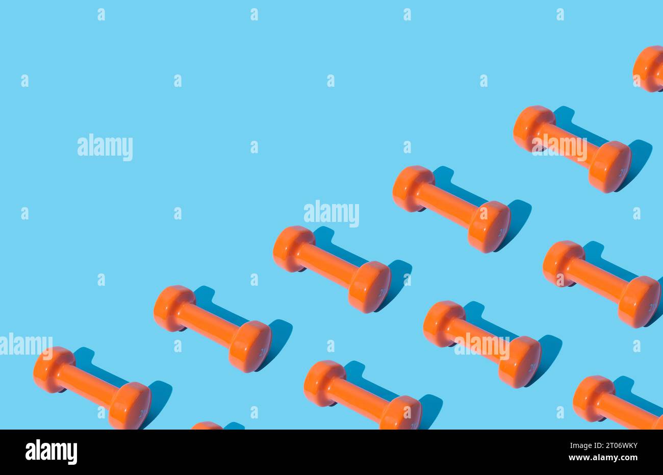 Creative pattern composition made of orange dumbbells on light blue ...