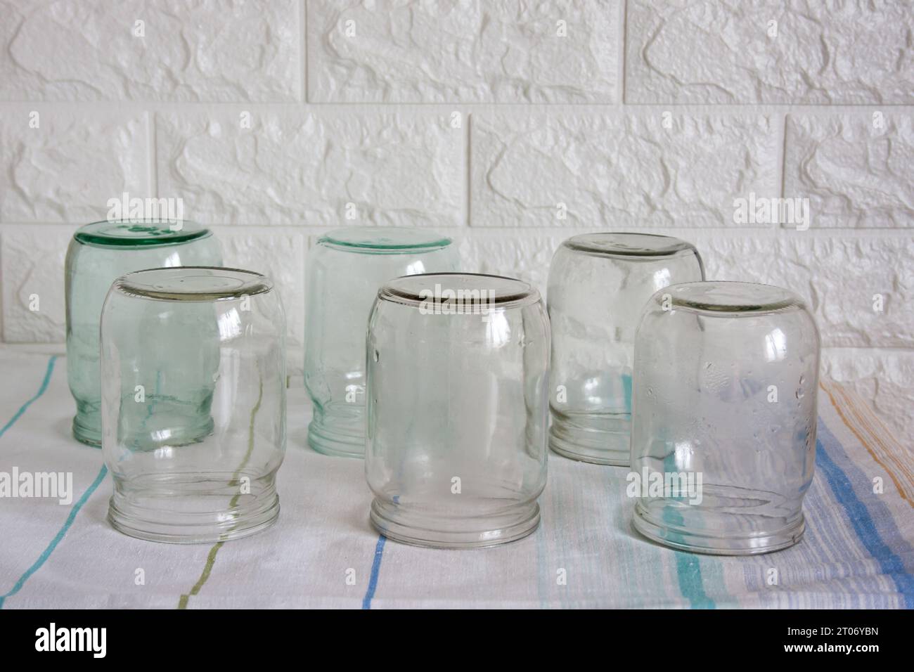 Several clean, empty half-litre glass jars sit upside down on the ...