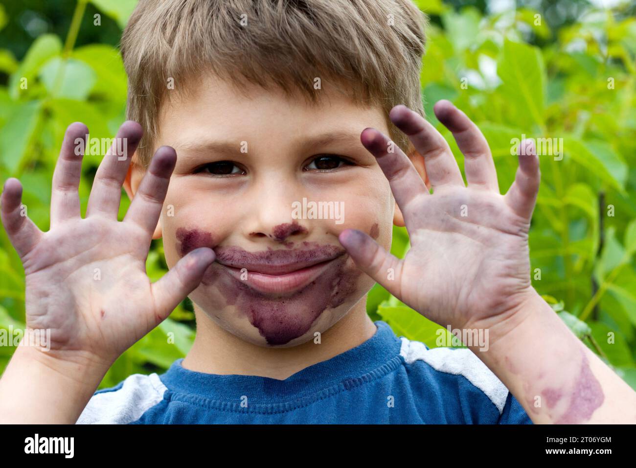 Close-up portrait of child whose face and hands are stained with black ...
