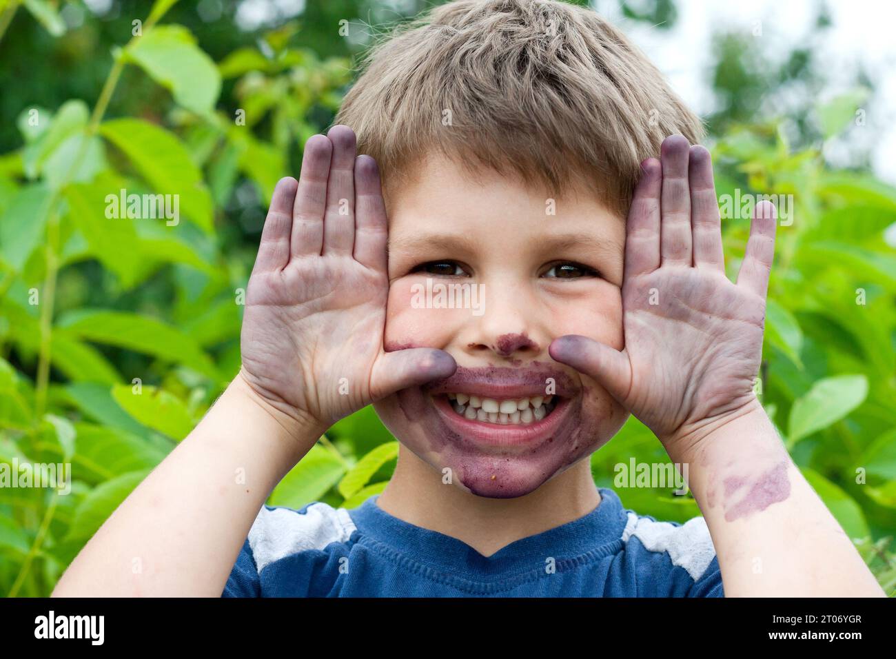 Close-up portrait of child whose face and hands are painted with black ...