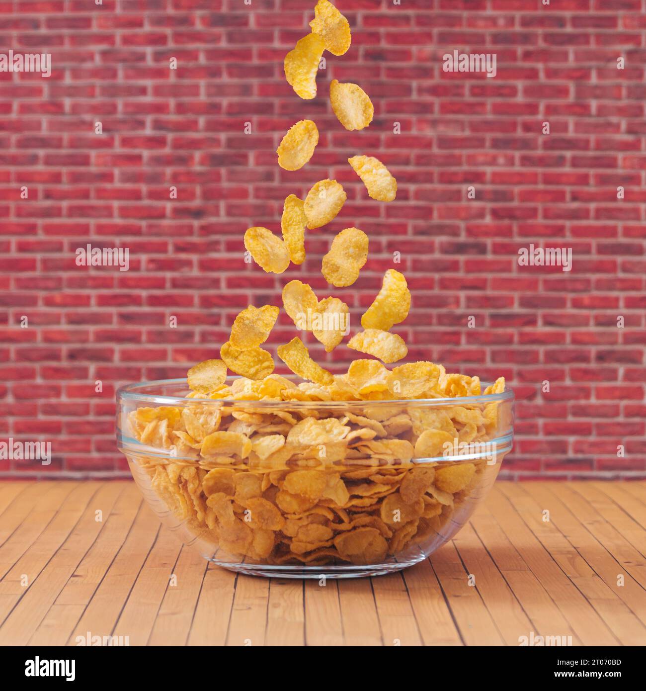 Creative layout made of healthy corn flakes falling into glass bowl ...