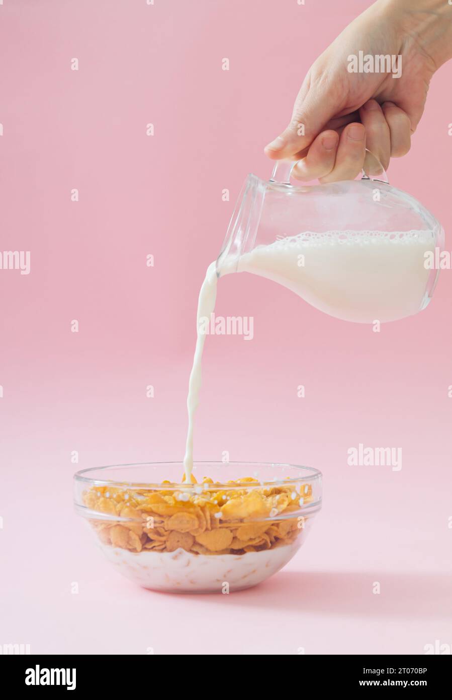 Creative composition with hand pouring milk into glass bowl full of ...