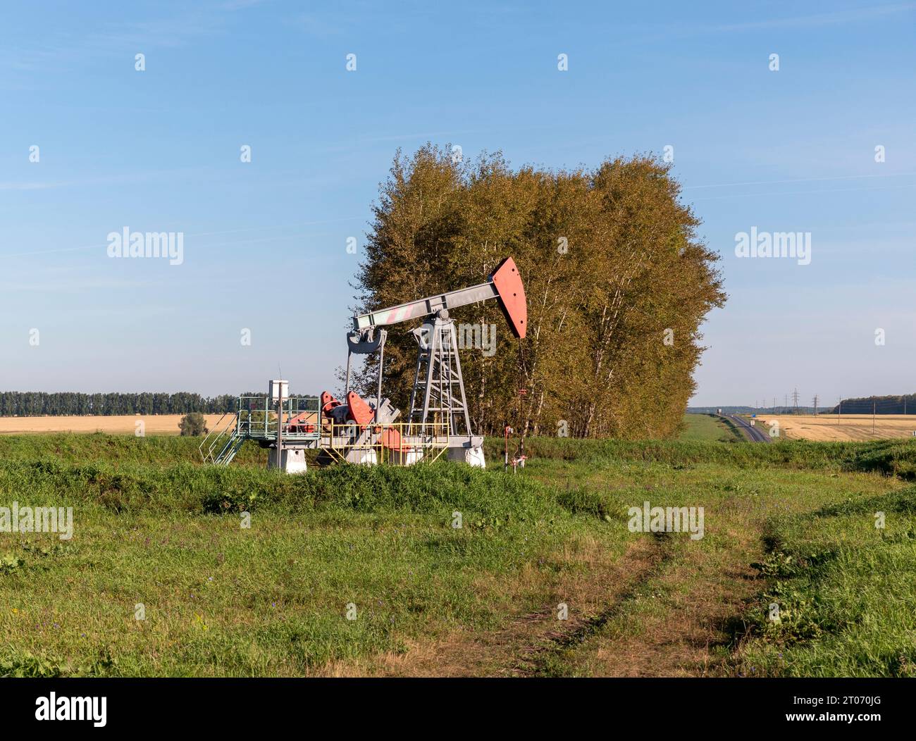 Operating oil and gas well in oil field, profiled against the blue sky ...