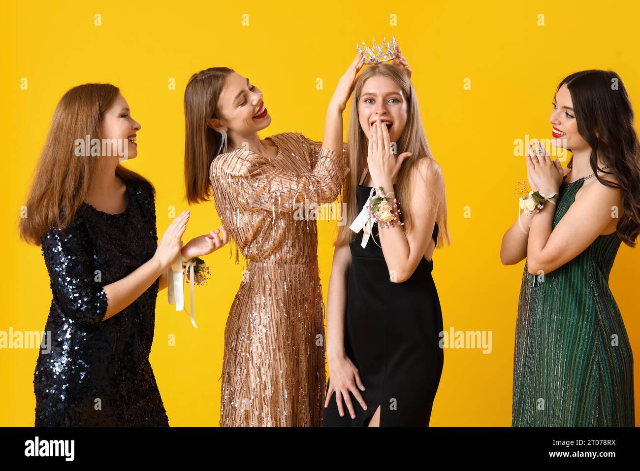 Young women crowning prom queen on yellow background Stock Photo - Alamy