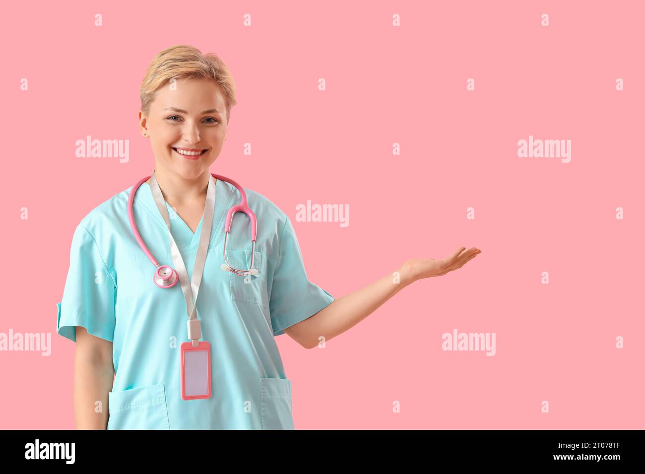 Female medical intern showing something on pink background Stock Photo ...