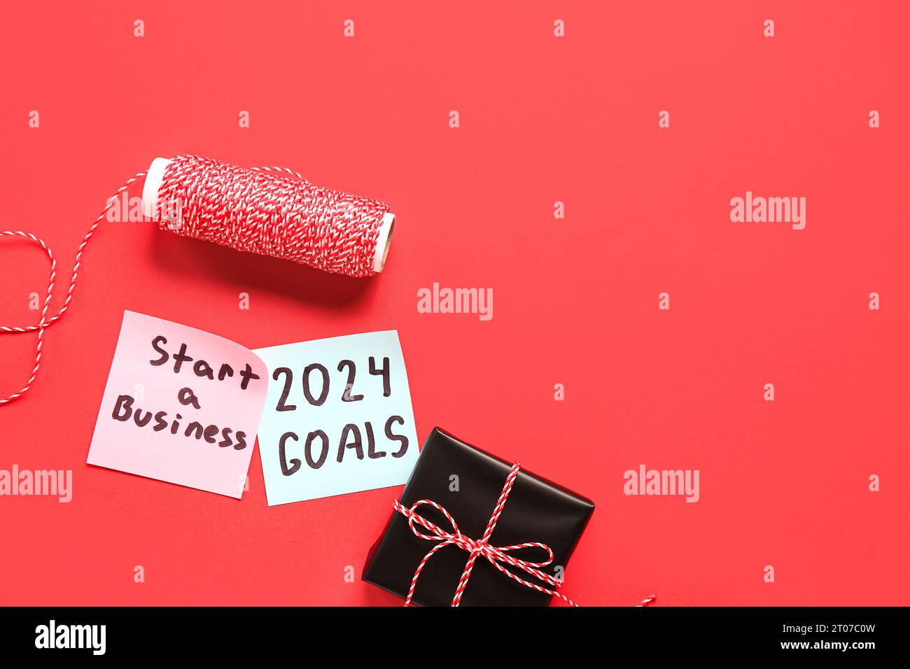 Sticky notes with goals for 2024, gift box and decorative rope on red ...