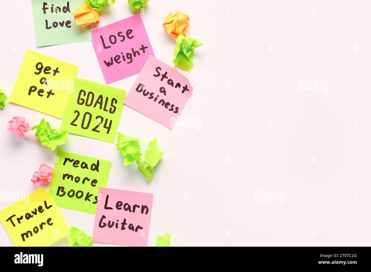 Sticky notes with different goals for 2024 and crumpled papers on white ...