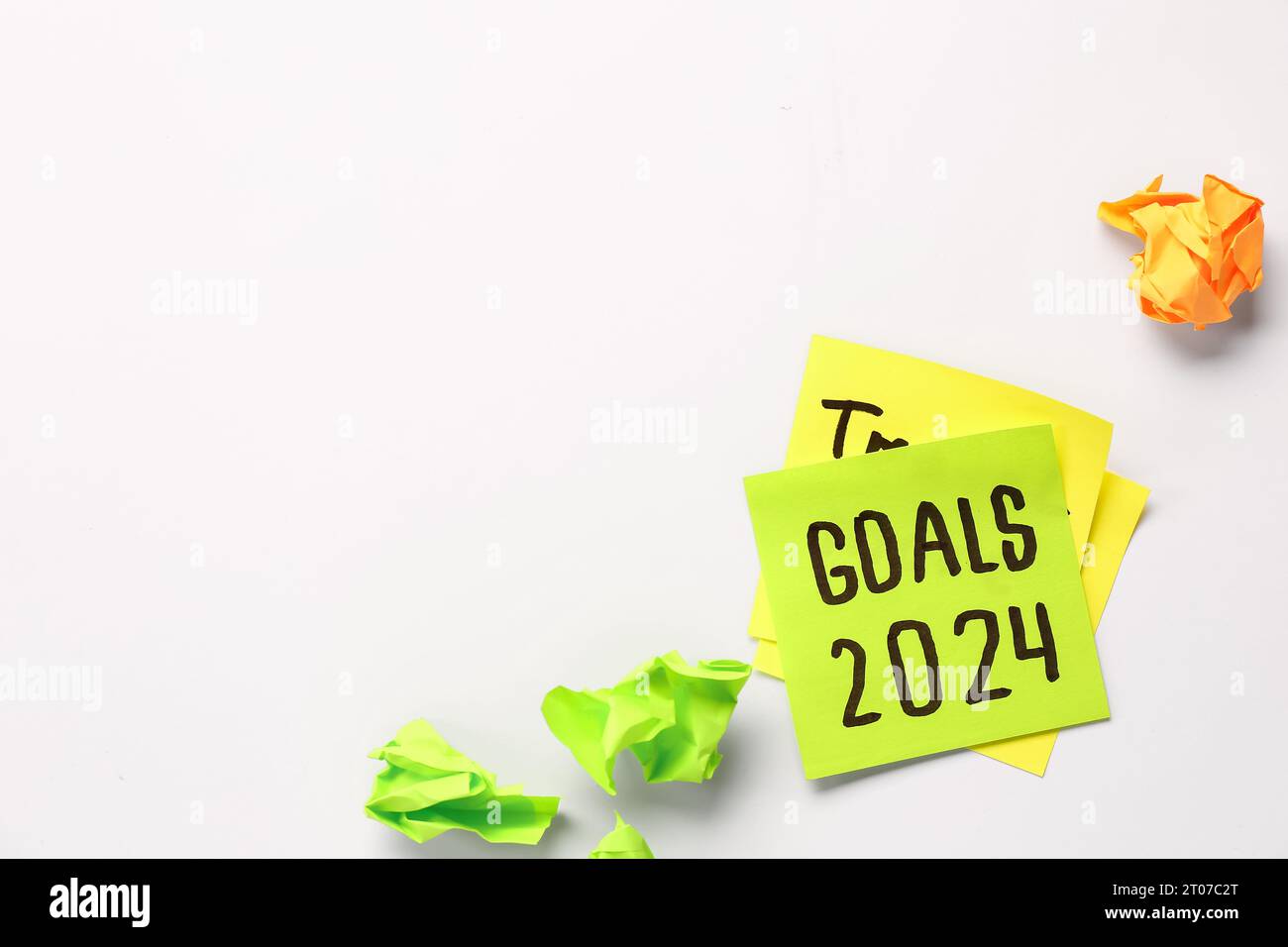 Sticky notes with different goals for 2024 and crumpled papers on white ...