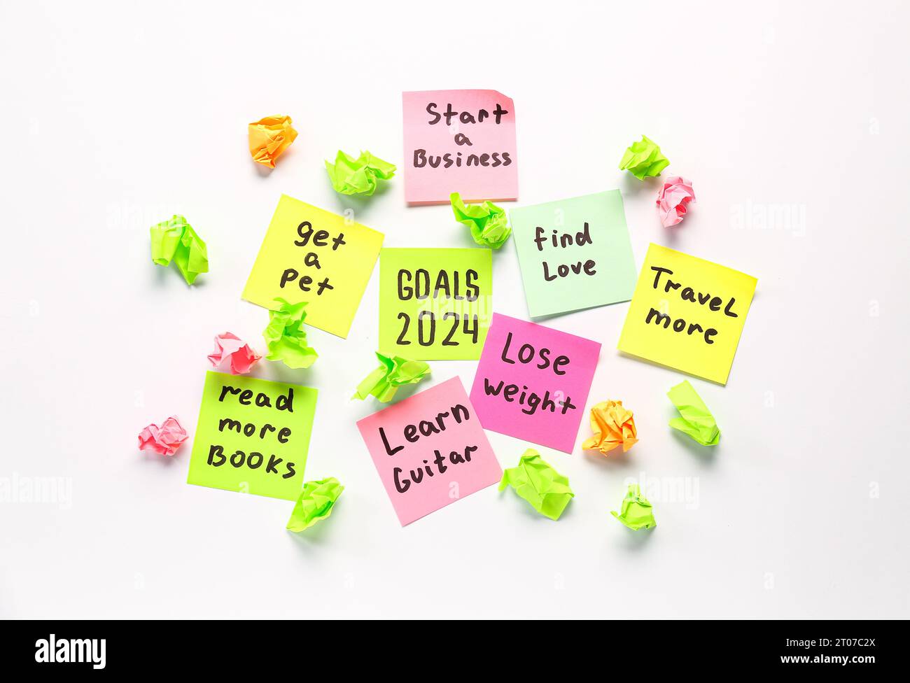 Sticky notes with different goals for 2024 and crumpled papers on white ...