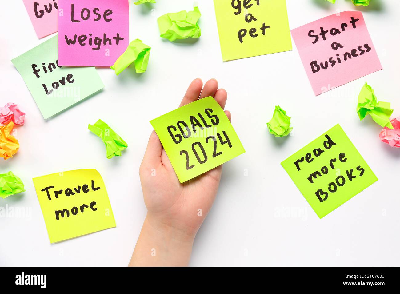 Female hand with sticky notes of different goals for 2024 and crumpled ...