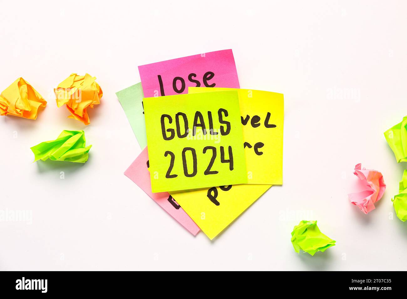 Sticky notes with different goals for 2024 and crumpled papers on white ...
