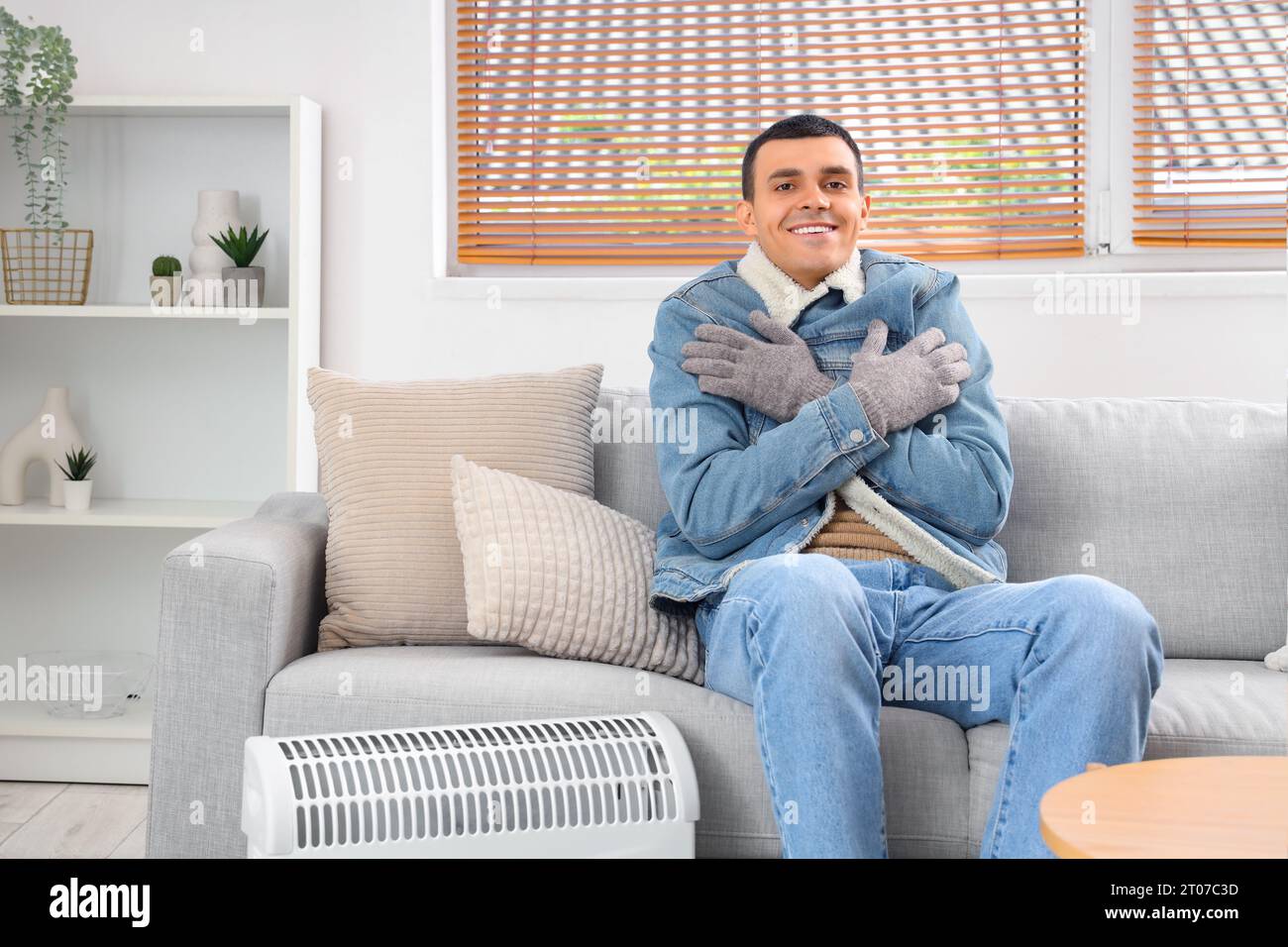 Frozen young man warming near radiator at home Stock Photo - Alamy