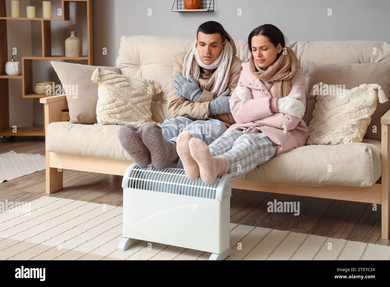 Young couple warming legs on radiator at home Stock Photo - Alamy