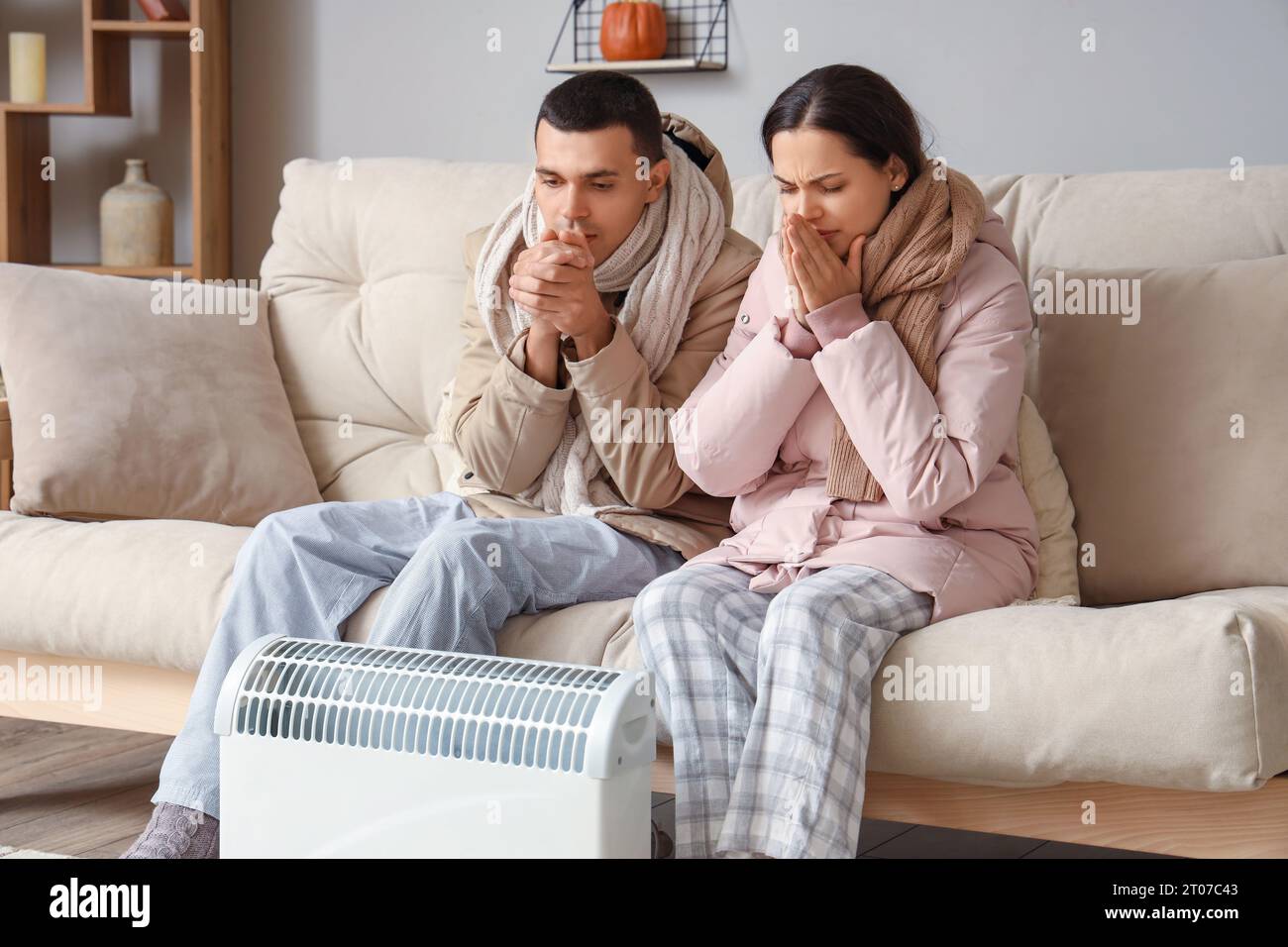 Frozen young couple warming near radiator at home Stock Photo - Alamy