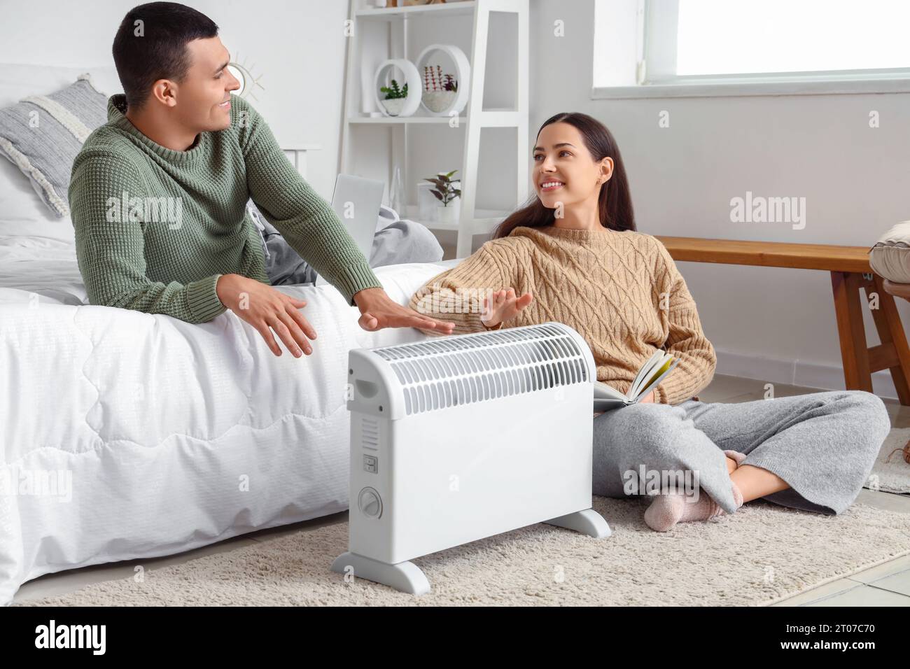 Young couple warming hands near radiator in bedroom Stock Photo - Alamy
