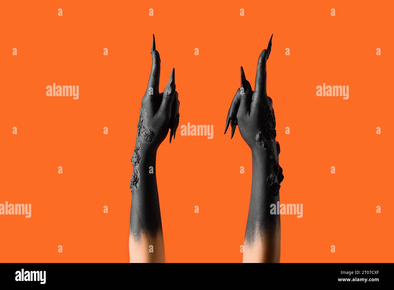 Black hands of witch pointing at something on orange background ...