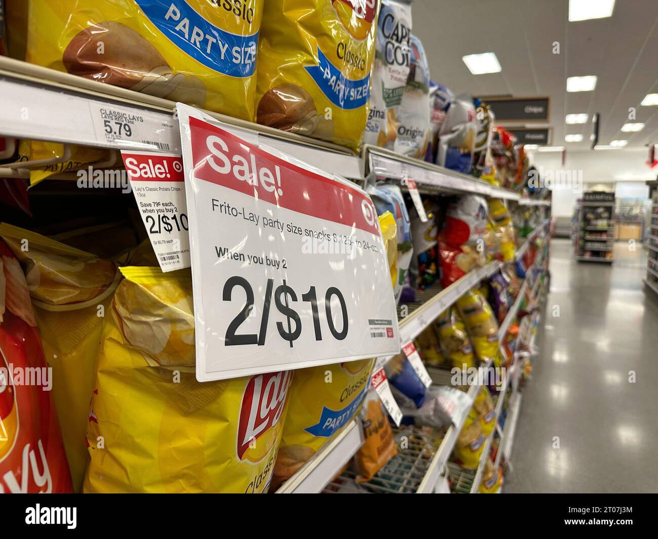 A sale sign hangs below a long shelf of potato chips on display in a ...