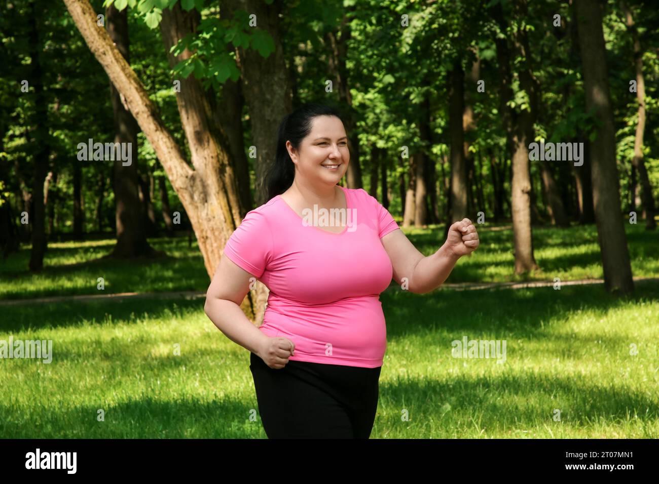 Happy overweight woman doing exercise in park Stock Photo - Alamy
