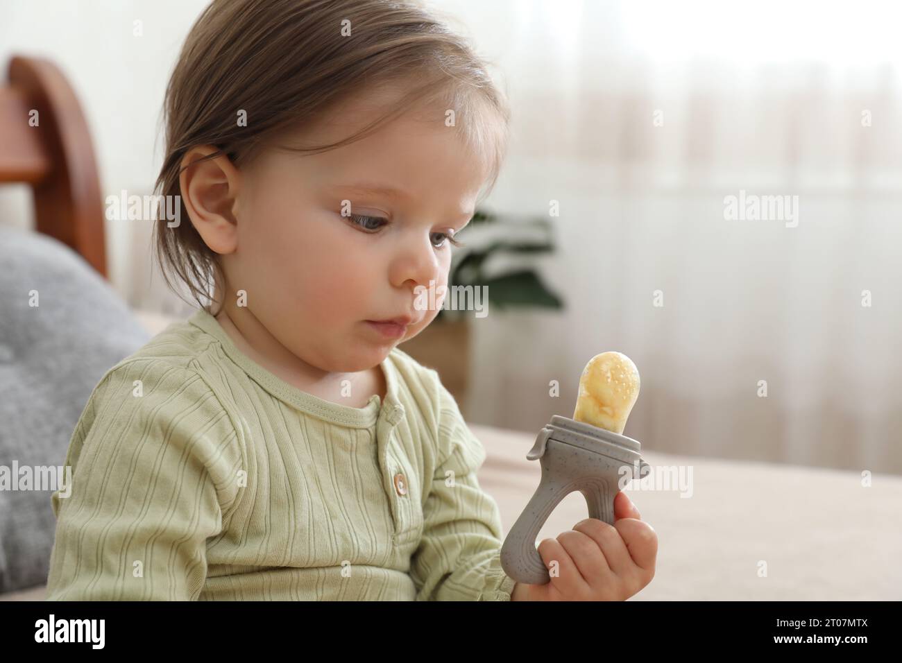 Cute baby girl with nibbler at home Stock Photo - Alamy