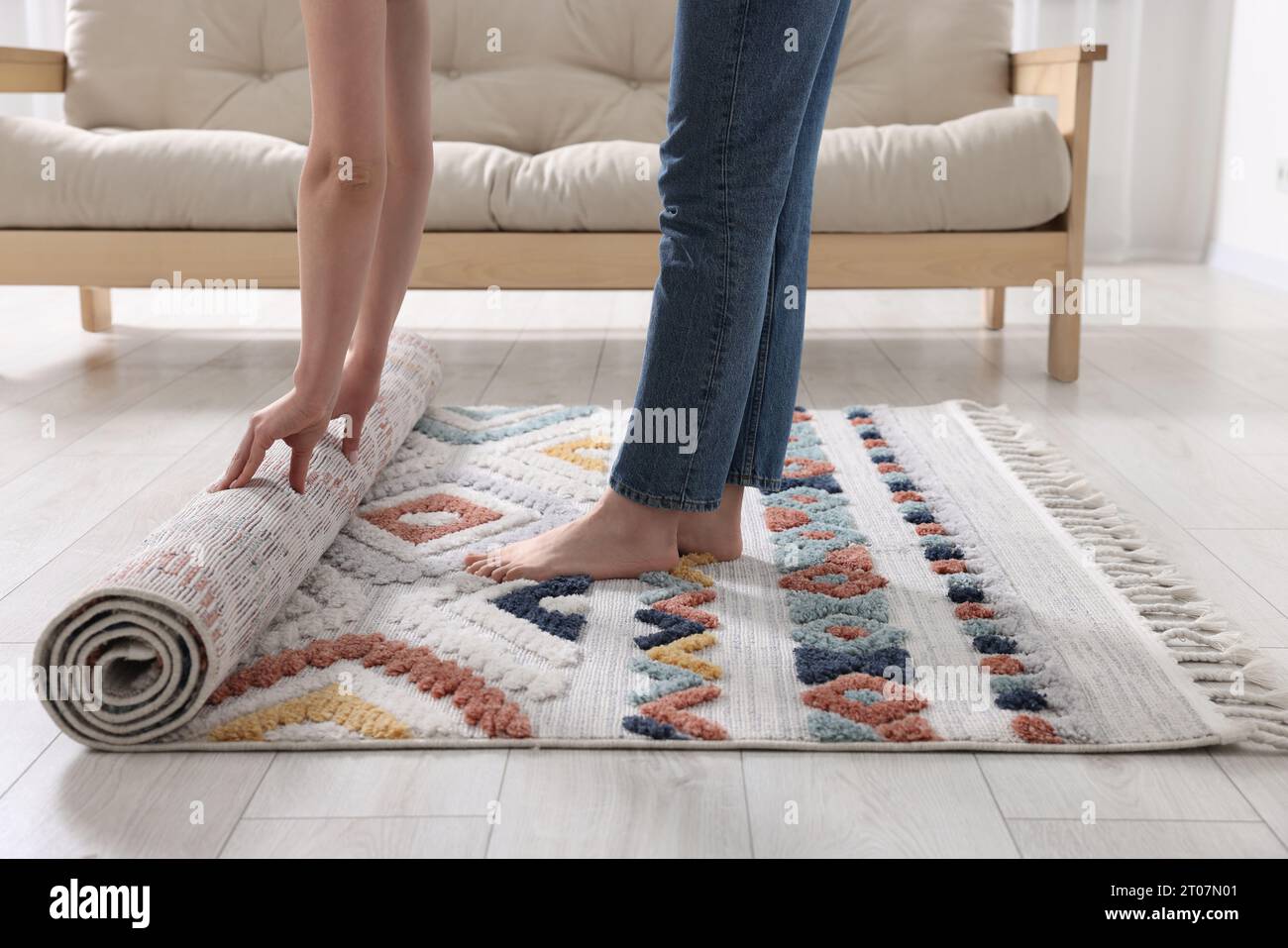 Woman unrolling carpet with beautiful pattern on floor in room, closeup ...