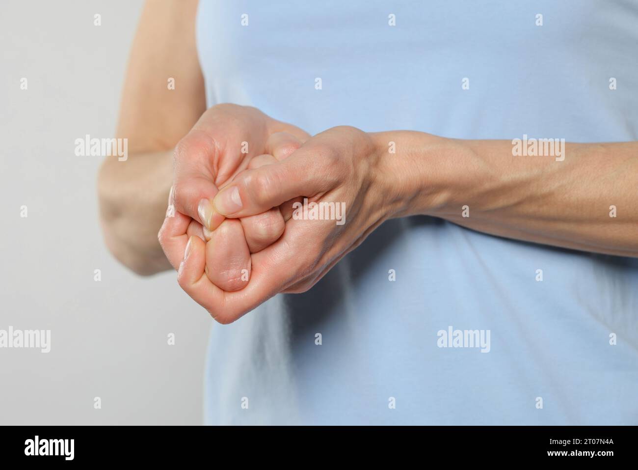 Woman cracking her knuckles on light grey background, closeup. Bad ...