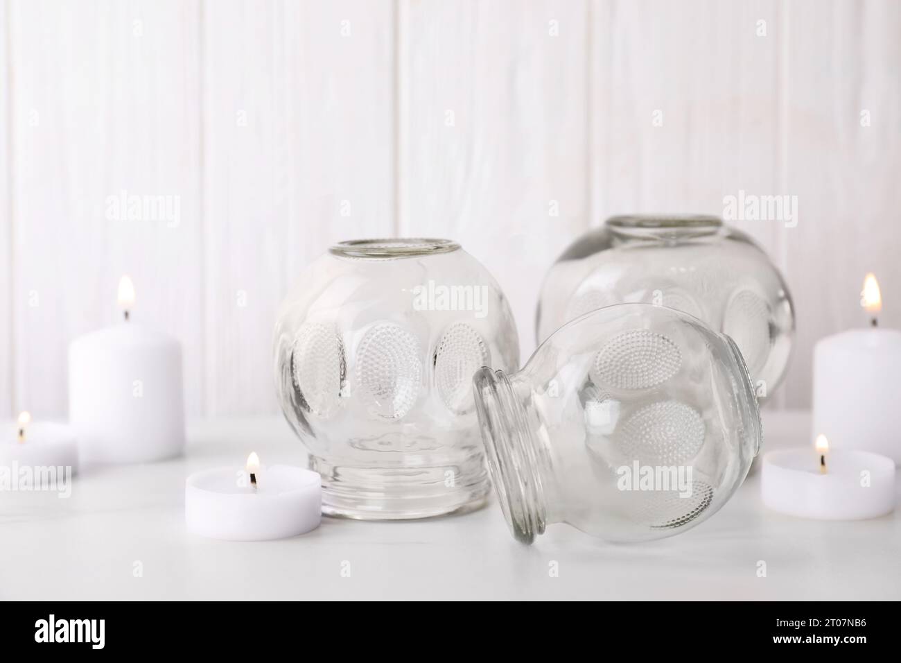 Glass cups and burning candles on white table. Cupping therapy Stock ...