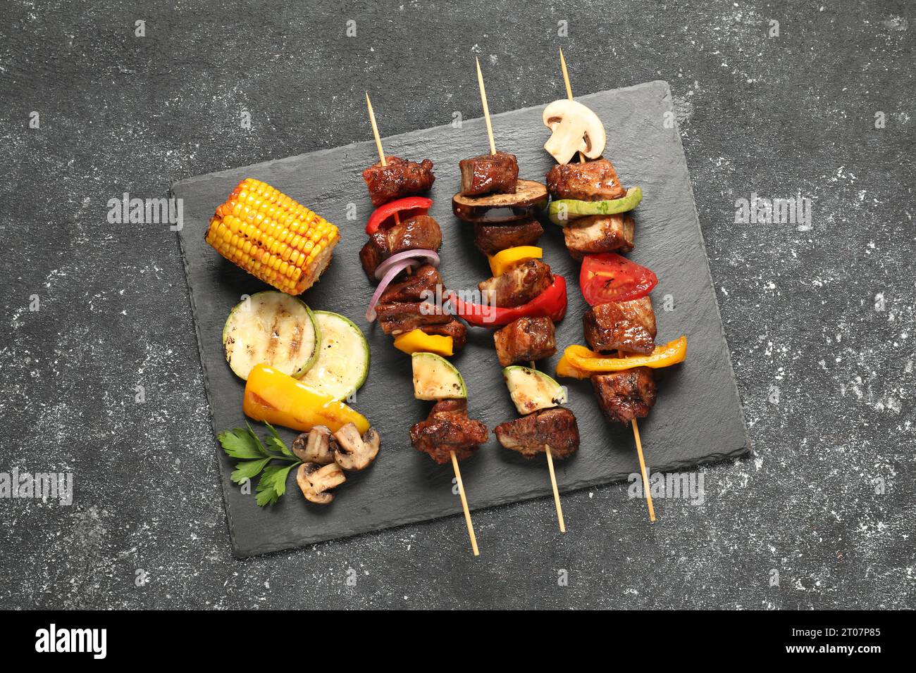 Delicious shish kebabs with grilled vegetables on grey textured table ...