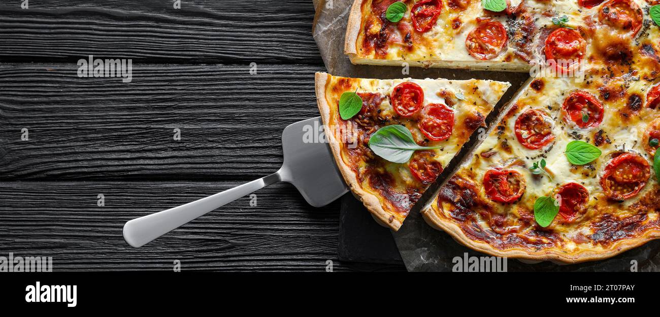 Cut delicious homemade quiche with prosciutto and server on black ...