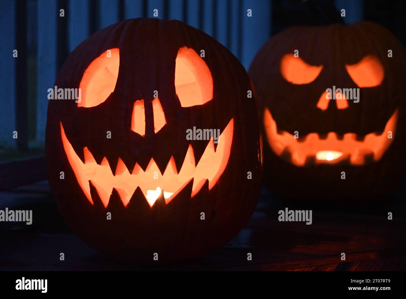 Carved pumpkins glow on the front porch of a home during Halloween ...