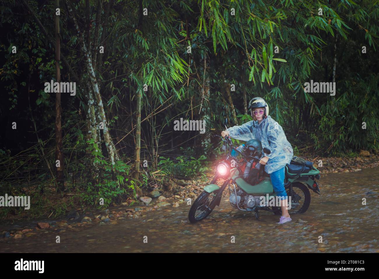 pretty woman riding small enduro motorcycle crossing shallow creek ...