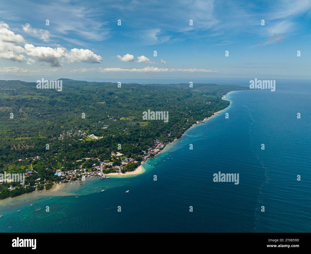 Coastline area with a white sandy beach and blue sea. Blue sky and clouds. Samal Island. Davao ...